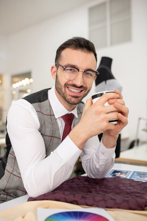 Male Tailor Sitting at the Table, Holding Cup, Smiling Stock Photo ...