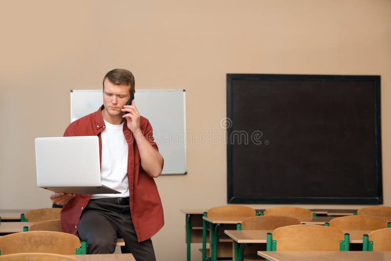 Male Teacher Talking on Phone in Classroom Stock Image - Image of ...