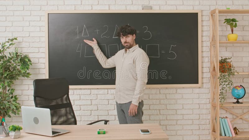 A Male Teacher is Teaching a Math Class and Explaining Equations ...