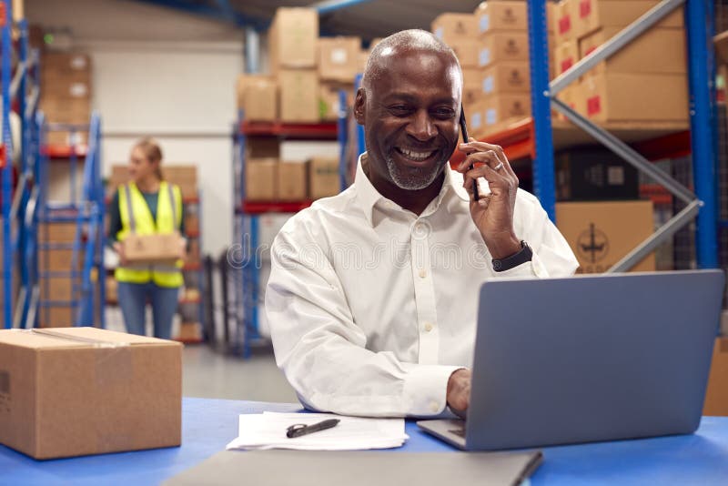 Male Team Leader Working on Laptop Talking on Mobile Phone Stock Photo ...