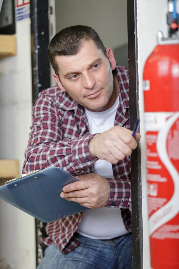 Male Technician Checking Red Fire Extinguisher Stock Image - Image of ...