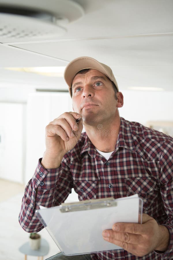 Male Technician Looking at Smoke Detector and Taking Notes Stock Photo ...