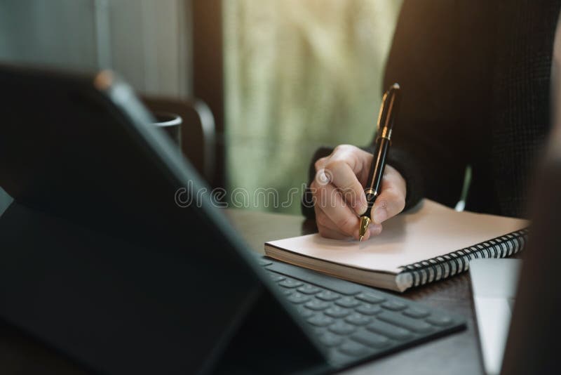 Male Use a Tablet Computer and Take Notes in the Notebook at the Office ...