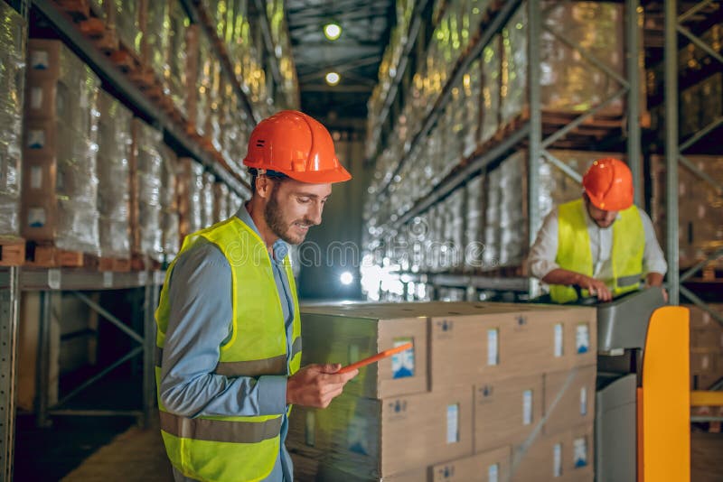 Male Warehouse Workers in Helmets Standing Near Cardboard Boxes Stock ...