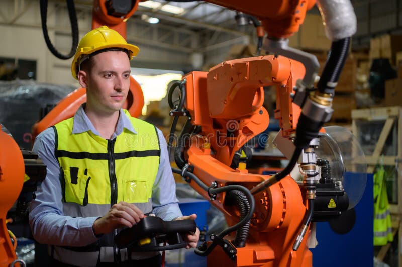 A Male Worker is Controlling a Welding Robot. Stock Image - Image of ...