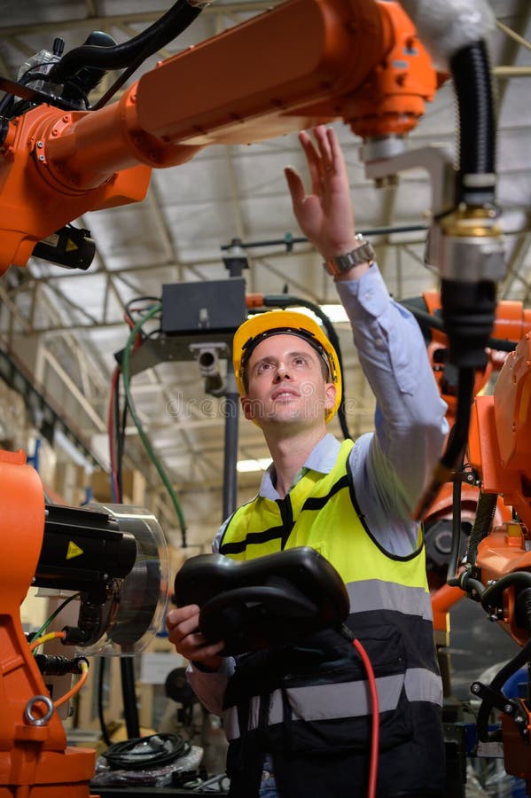A Male Worker is Controlling a Welding Robot. Stock Image - Image of ...