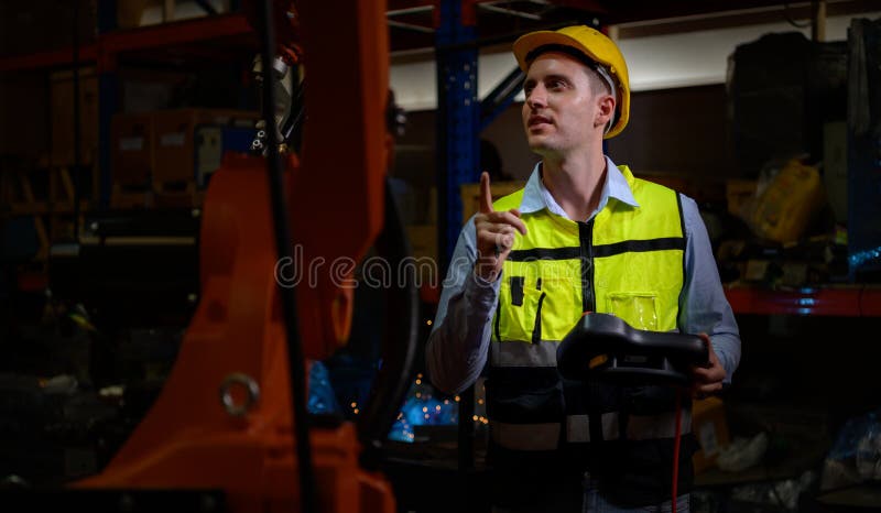 A Male Worker is Controlling a Welding Robot. Stock Image - Image of ...