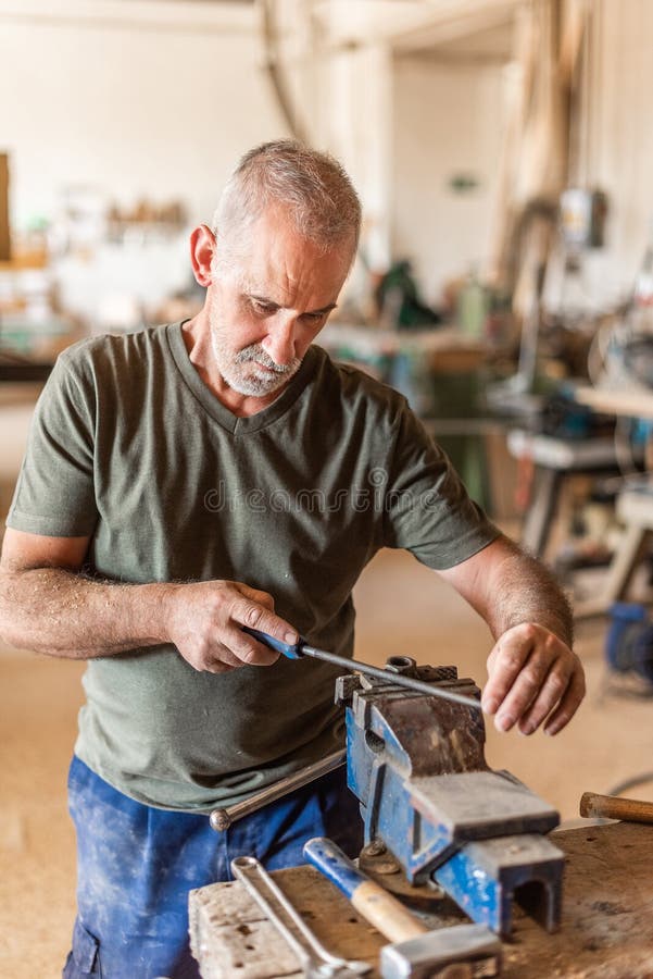 Male Worker Filing a Metal Tool Over a Workbench Stock Photo - Image of ...