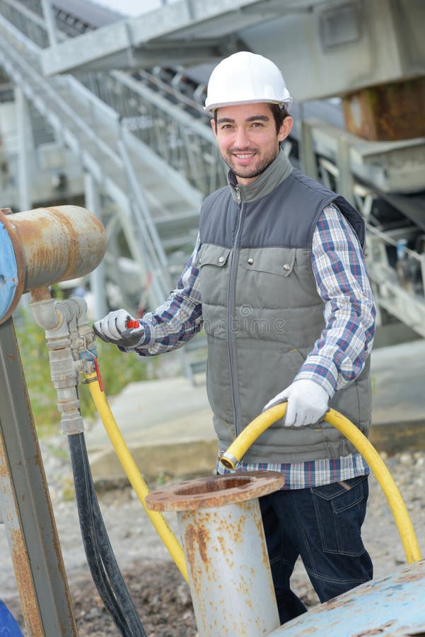 Male worker holding hose stock image. Image of company - 277792865