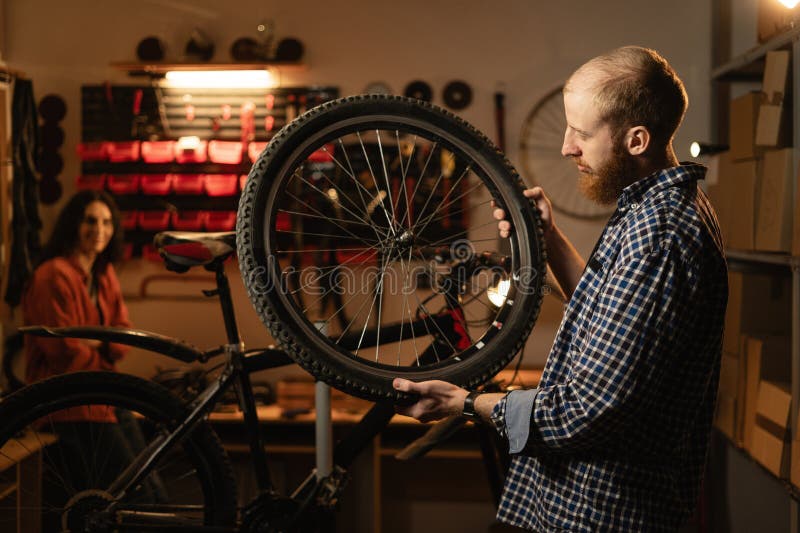 Male Worker Holding and Repairing Bicycle Wheel while Standing in ...