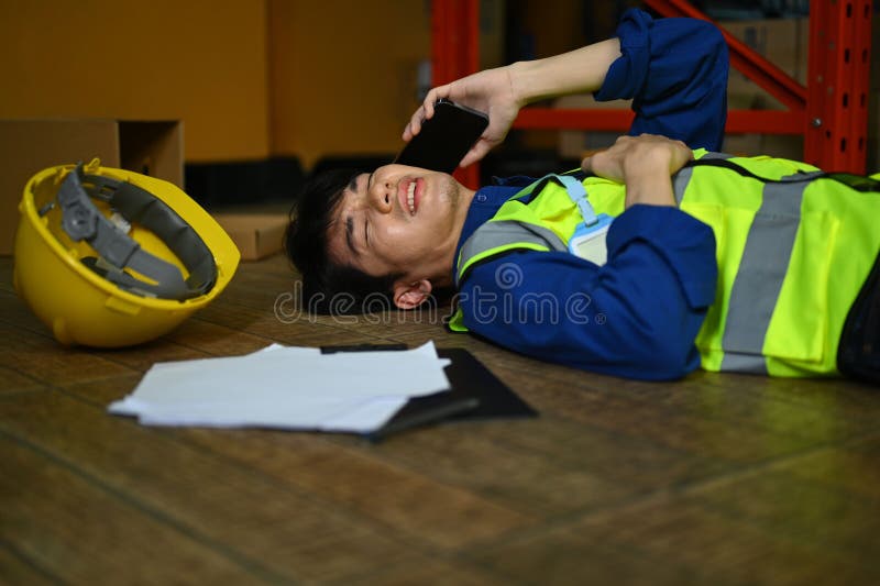 Male Worker Lying on Floor in Warehouse after an Accident and Making an ...