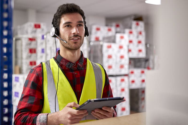 Male Worker Wearing Headset in Logistics Distribution Warehouse Using ...