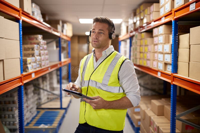 Male Worker Wearing Headset in Logistics Distribution Warehouse Using ...