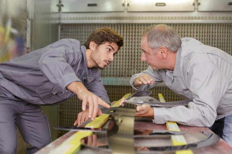 Male Workers in Discussion while Leaning Across Machinery Stock Photo ...