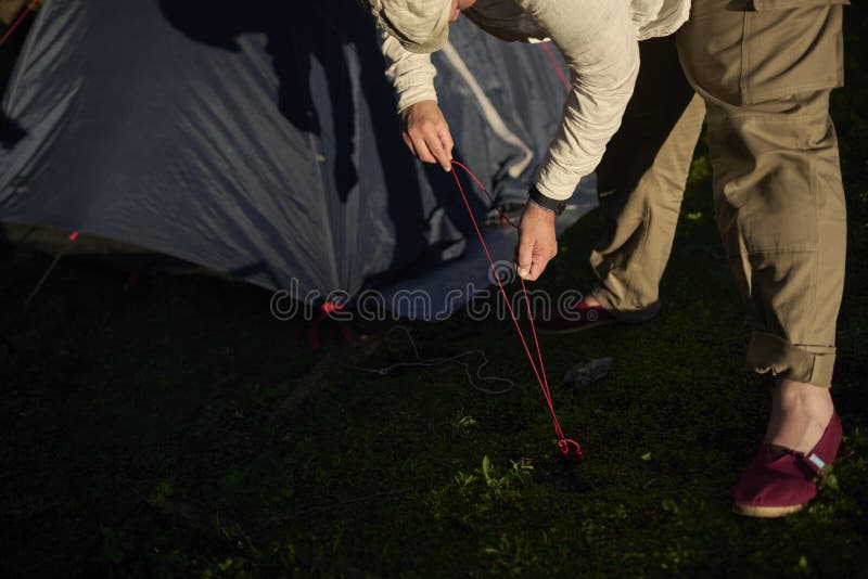 Man Adjusting the Tension of the Guy Ropes of His Tent at Sunset Stock ...
