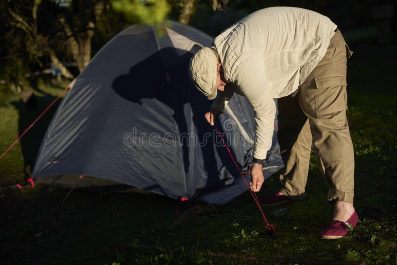 Man Adjusting the Tension of the Guy Ropes of His Tent at Sunset Stock ...