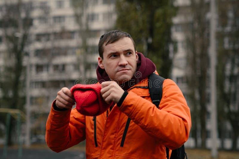 Man Adjusts Red Hat while Exploring Abandoned Location on a Cloudy Day ...