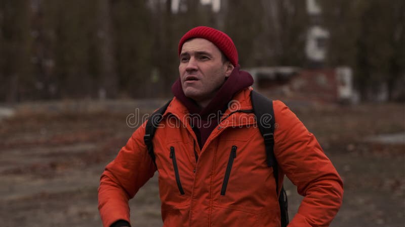 Man Adjusts Red Hat while Exploring Abandoned Location on a Cloudy Day ...