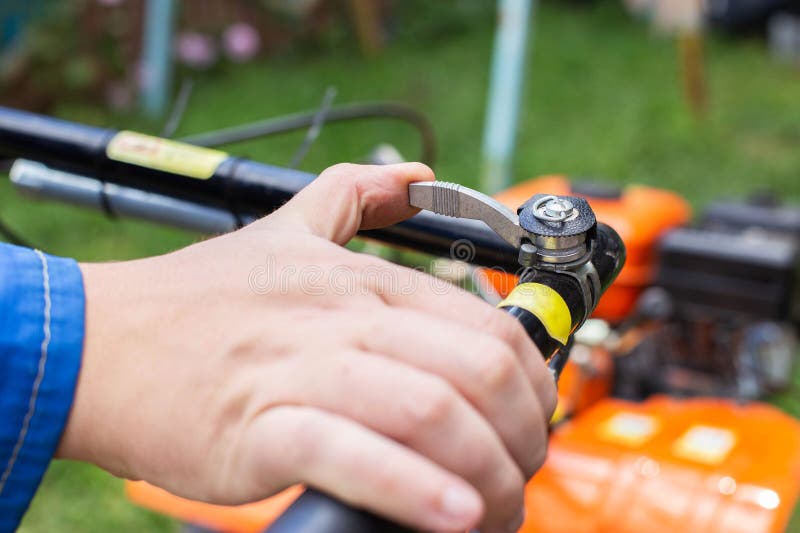 A Man Adjusts the Throttle on the Handle of a Walk-behind Tractor ...
