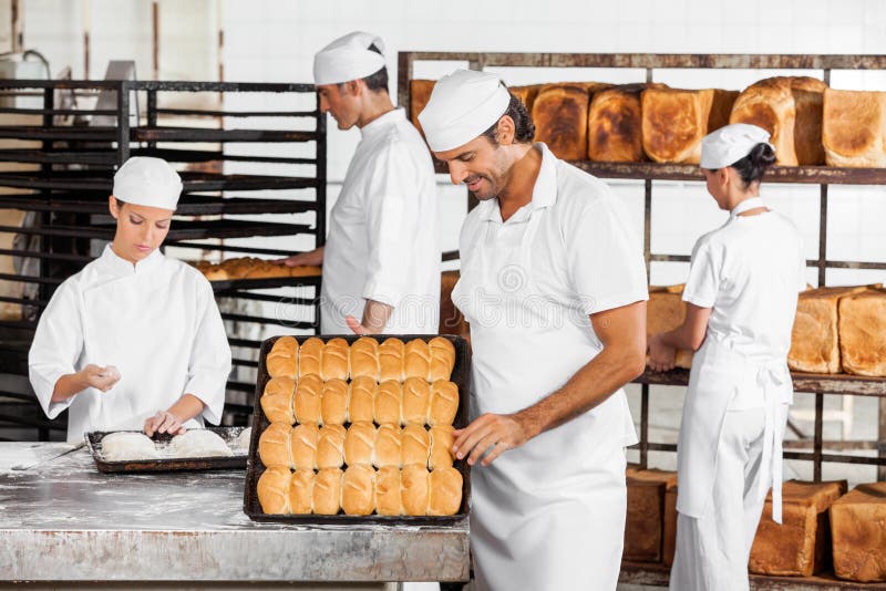 Man Analyzing Breads while Colleagues Working in Bakery Stock Photo ...