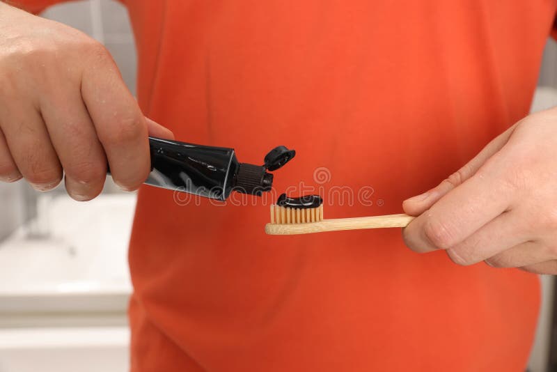 Man Applying Charcoal Toothpaste Onto Toothbrush in Bathroom, Closeup ...