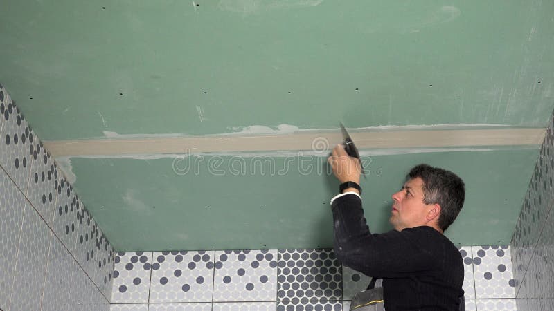 Man Applying Joint Compound between Drywall Panels and Ceiling Heads ...