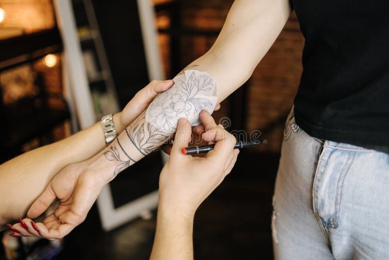 Man Applying a Tattoo Stencil on Woman Hand. Tattoo Artist Begin Work ... Man Applying a Tattoo Stencil on Woman Hand. Tattoo Artist Begin Work ...