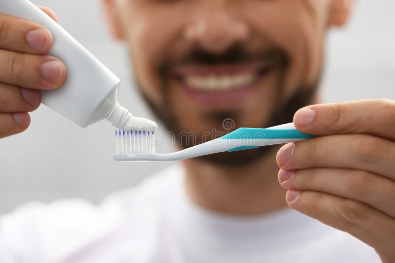 Man Applying Toothpaste on Brush Against Blurred Background, Closeup ...