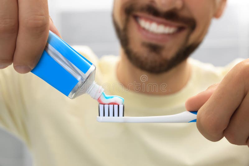 Man Applying Toothpaste on Brush Against Blurred Background, Closeup ...