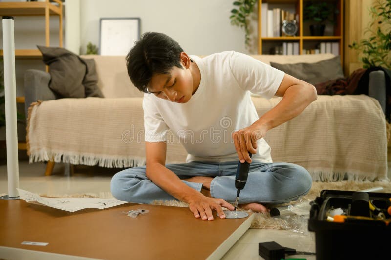 Man Assembling a Piece of Furniture Using an Electric Screwdriver in a ...