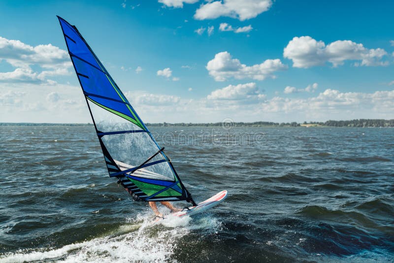 The Man Athlete Rides the Windsurf Over the Waves on Lake Stock Photo ...