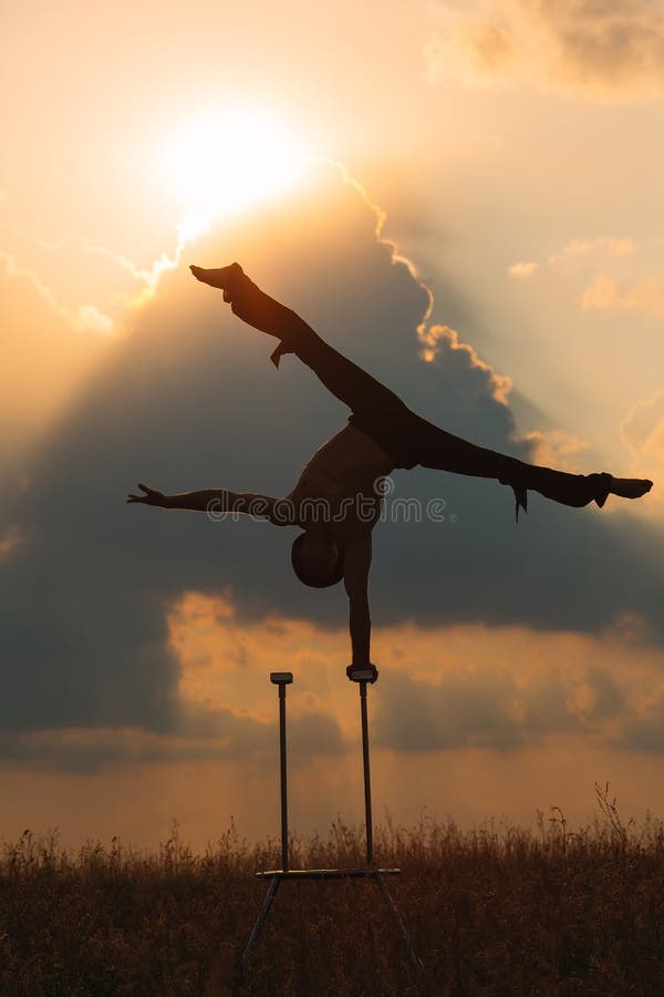 A Man of Athletic Build Performs Complex Gymnastic Exercises in a Field ...