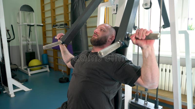 A Man with an Athletic Build is Working Out on a Machine in a Gym ...