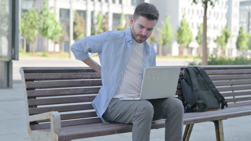 Young Man with Back Pain Using Laptop while Sitting on Bench Stock ...
