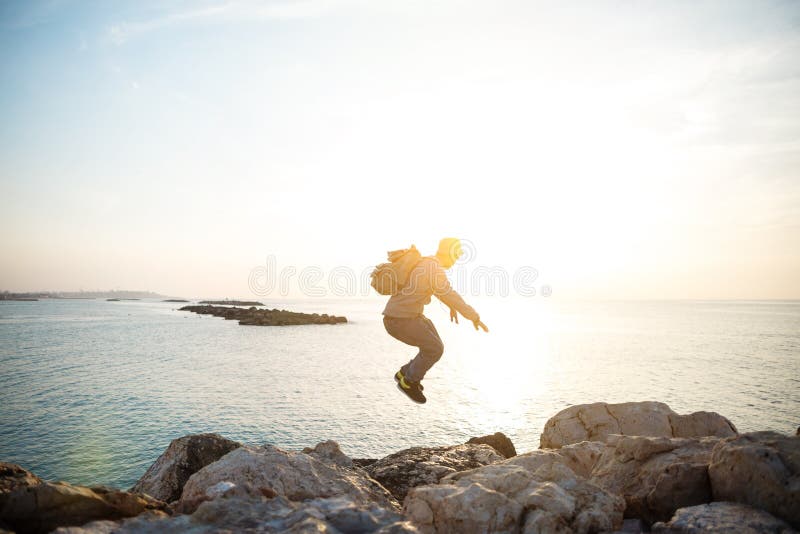 Man Jumping into the Water from Cliff at Sunset with Outspread Hands ...
