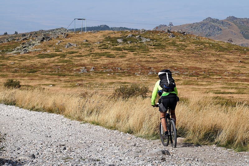 A Man with a Backpack Rides a Bicycle on a Mountain Road, Solo Travel ...
