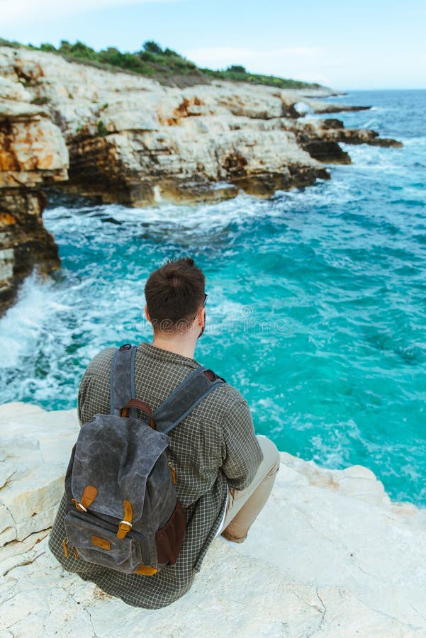 Man with Backpack Sitting on the Cliff Enjoying City View Stock Photo ...