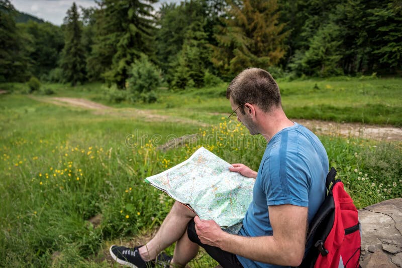 Man with Backpack Sitting on the Stone and Looking into Map Stock Image ...