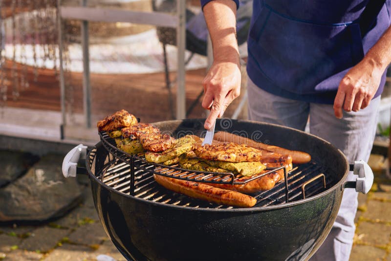 Man by the Barbeque with Pork Chops and Sausages Stock Image - Image of ...
