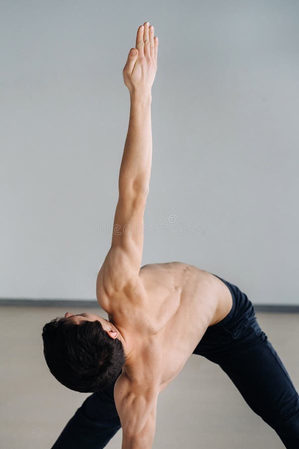 A Man with a Bare Torso Trains Standing Up, Doing Stretching in the Gym ...