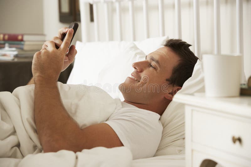 Man in Bed at Home Texting on Mobile Phone Stock Image - Image of ...