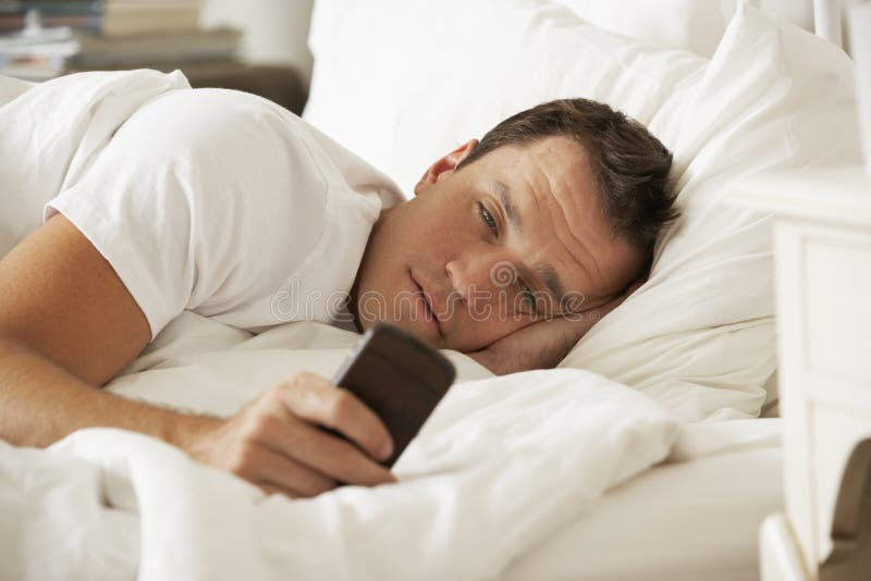 Man in Bed at Home Texting on Mobile Phone Stock Photo - Image of ...