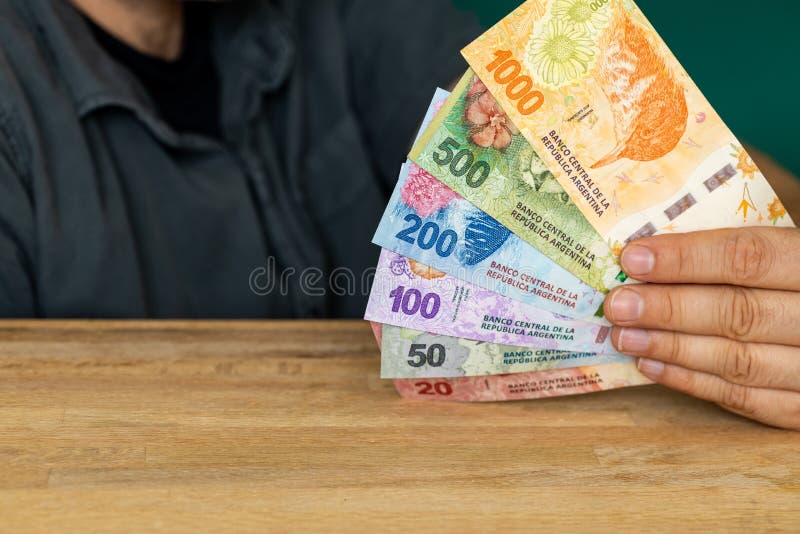 The Man Behind the Desk is Holding a Bundle of Argentinian Pesos ...