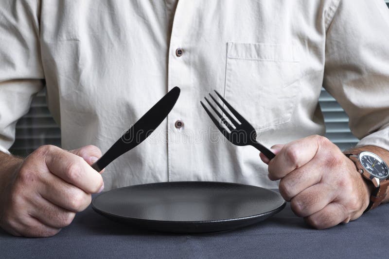 A Man in a Beige Shirt at a Table with a Black Empty Plate. Stock Photo ...