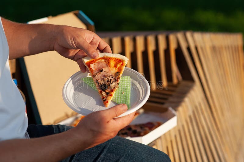 The Man on the Bench is Eating Pizza. Fast Food in the Fresh Air Stock ...