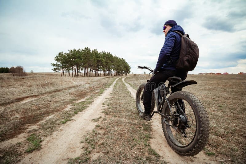 A Man on a Bicycle with Thick Wheels and an Electric Motor. Rural Area ...
