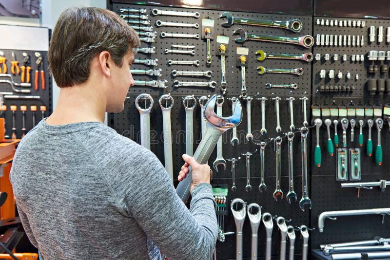 Man with Big Wrench Near Wall with Tools in Store Stock Image - Image ...
