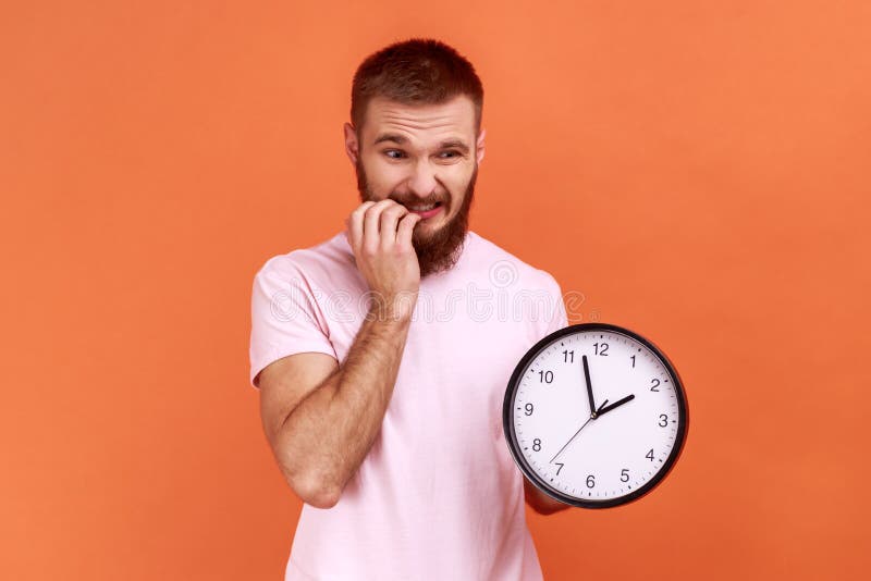 Man Biting Nails on His Fingers Holding Big Wall Clock in Hand, Worried ... Man Biting Nails on His Fingers Holding Big Wall Clock in Hand, Worried ...