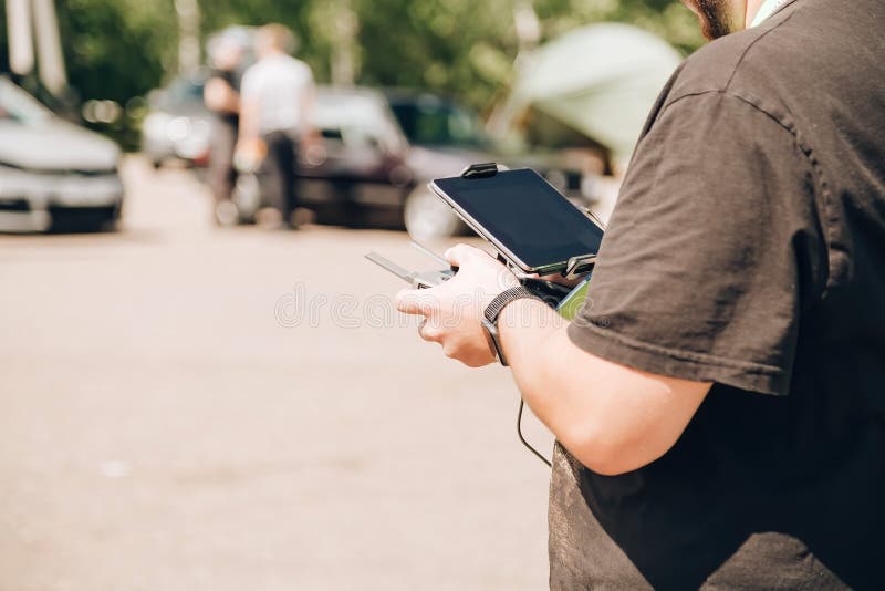 A Man in Black Controls a Drone Using a Remote Control and Tablet. he ...