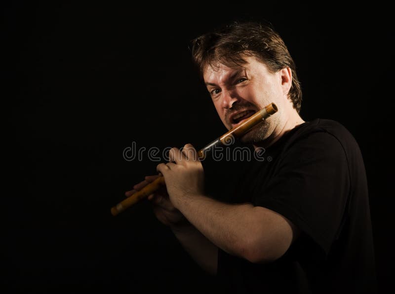 Man in black plays a flute stock image. Image of hand - 15132795